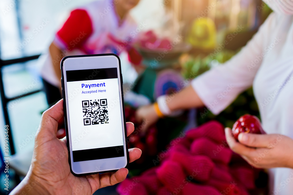 Scanning QR code payment with blurry staff and customer buying fruit in ...