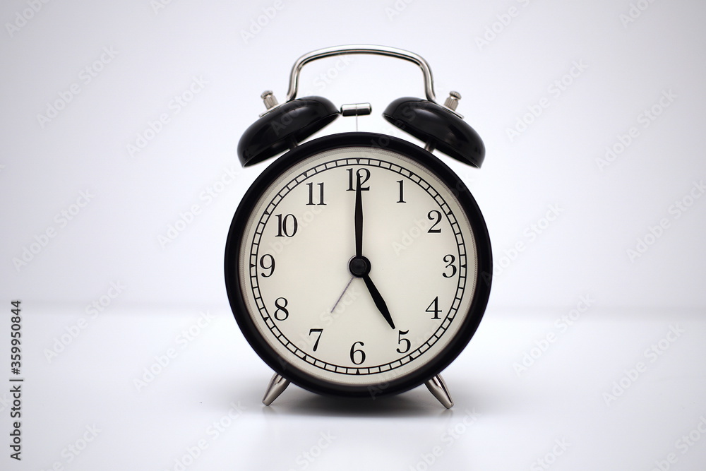Black vintage alarm clock on table. White background. Wake up concept ...