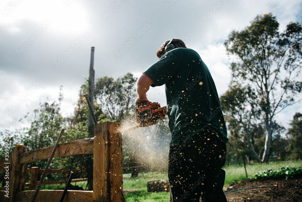Man using chainsaw, building post and rail fence Stock Photo | Adobe Stock