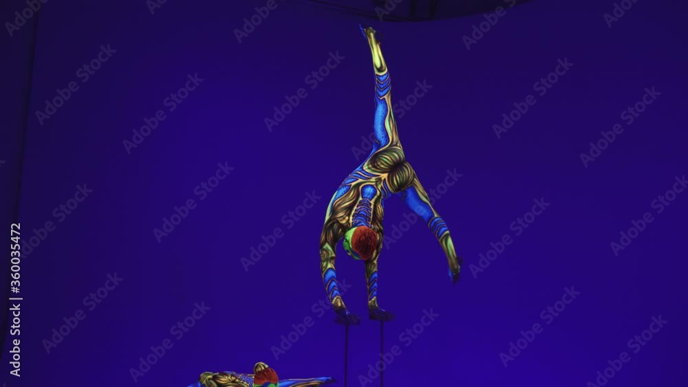 Acrobatic twins in neon costumes to perform a stand on the hands and ...
