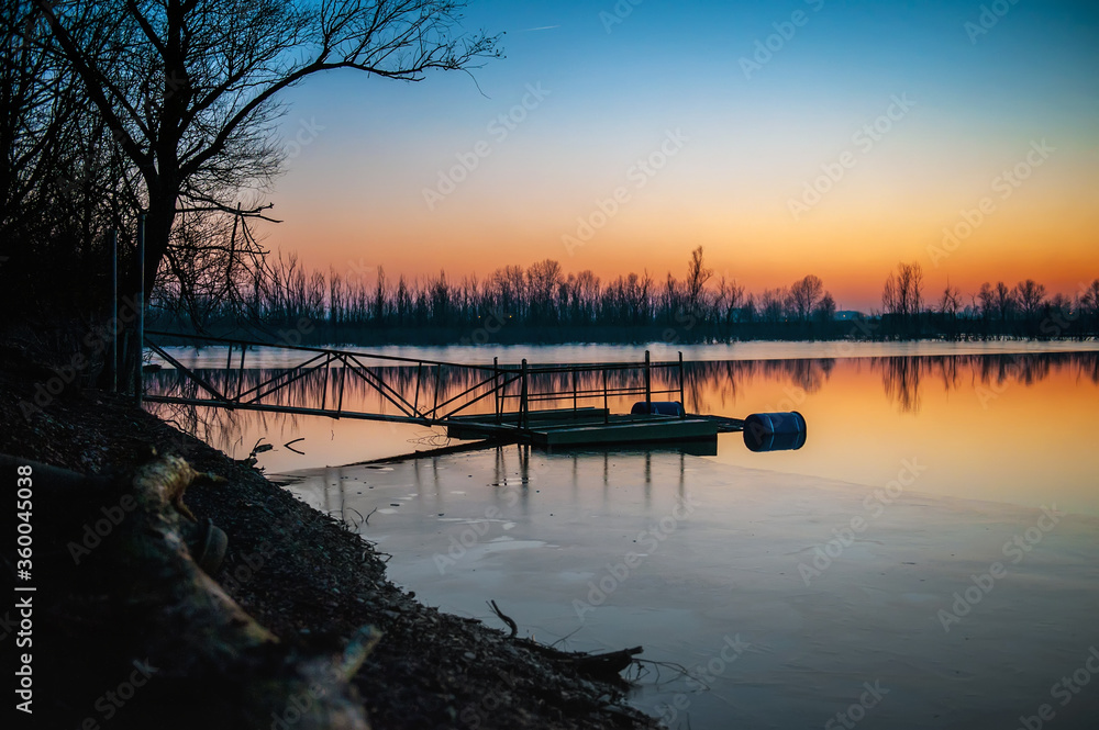 A iron pontoon on the lake partially frozen during sunset.nice shades ...