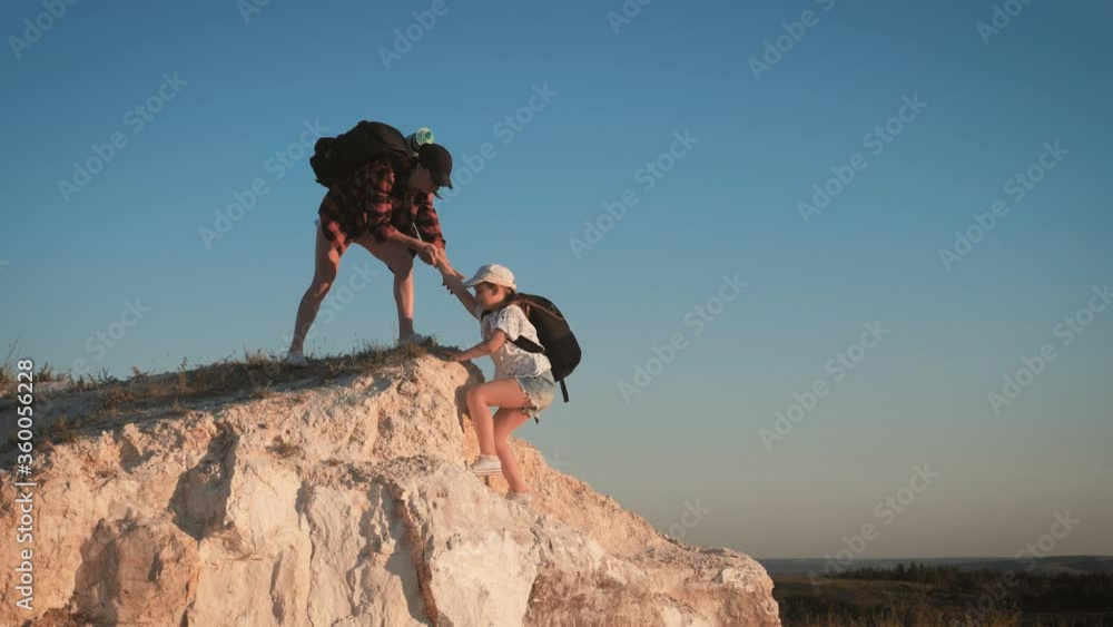 Girl helps her friend climb up the last section of mountain. Tourists ...