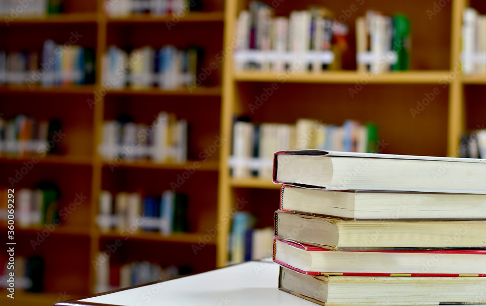 Stack of books and blurred bookshelf in the library, education ...