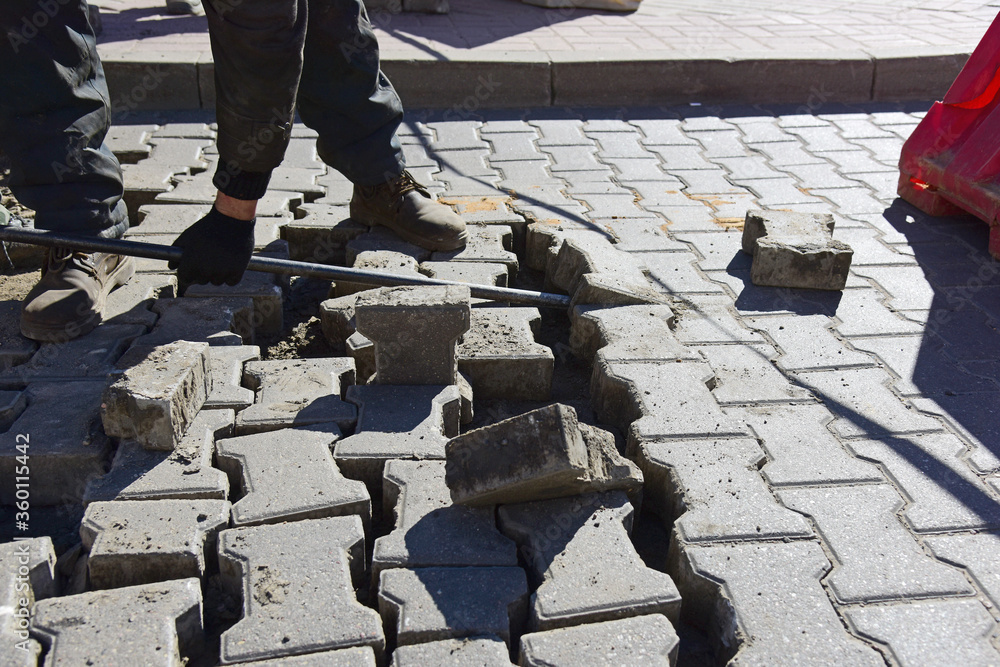 The builder raises the concrete slab with an iron rod, repairs the road ...