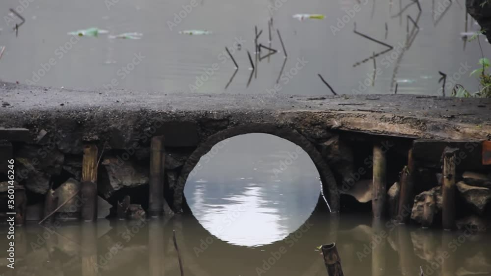 A stone dam on the river and a small semicircular bridge create a ...