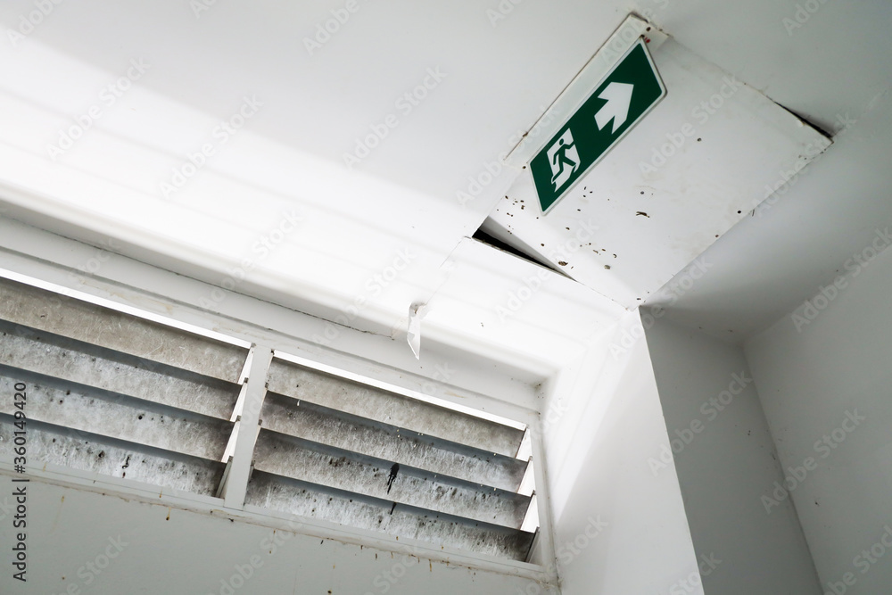Open ceiling panels in roof office building with emergency exit sign ...