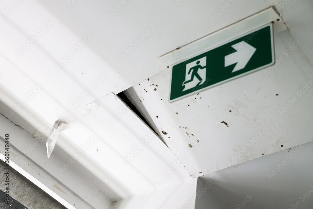 Open ceiling panels in roof office building with emergency exit sign ...