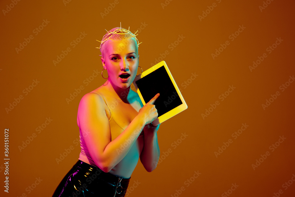 Pointing on blank screen. Young caucasian woman on brown studio ...