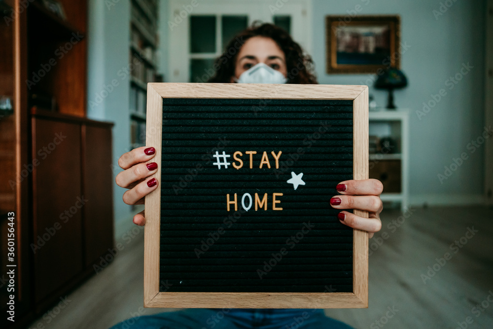 Young woman locked up at home with a blackboard in hand with the text ...