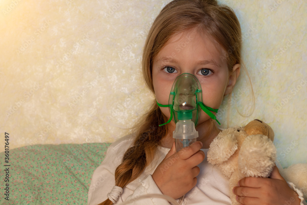 Little girl making inhalation with nebulizer on a bed at home. Sick ...