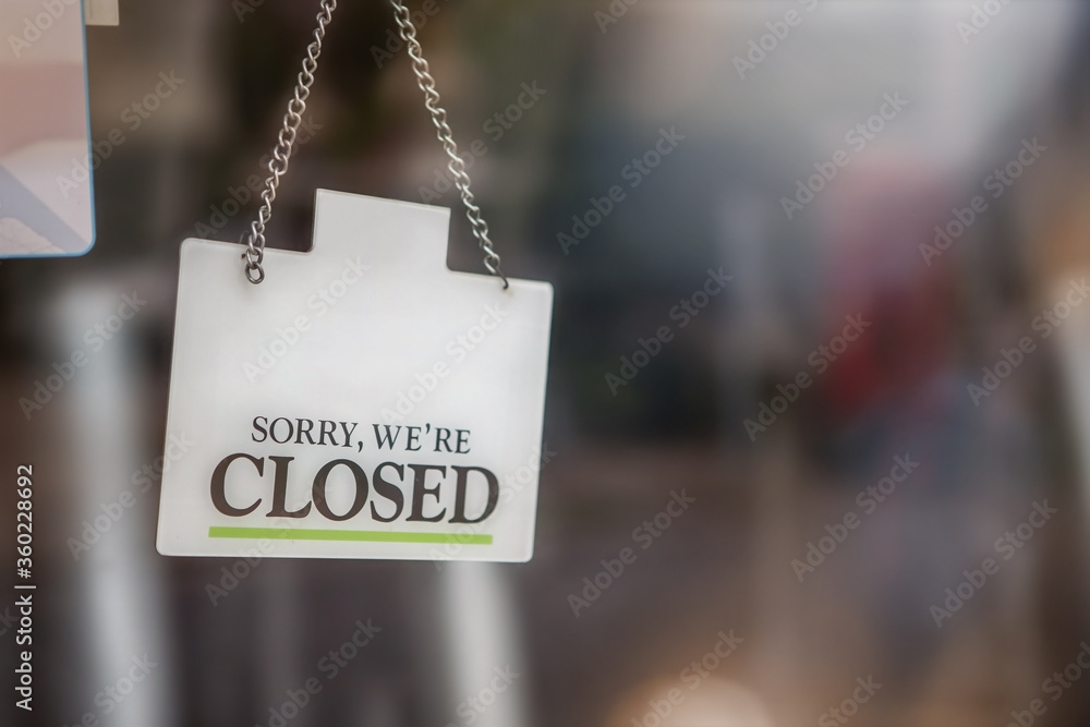 The Sorry we're closed message board on a glass door in front of small ...