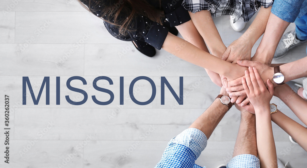 People holding hands together over light wooden background and text ...