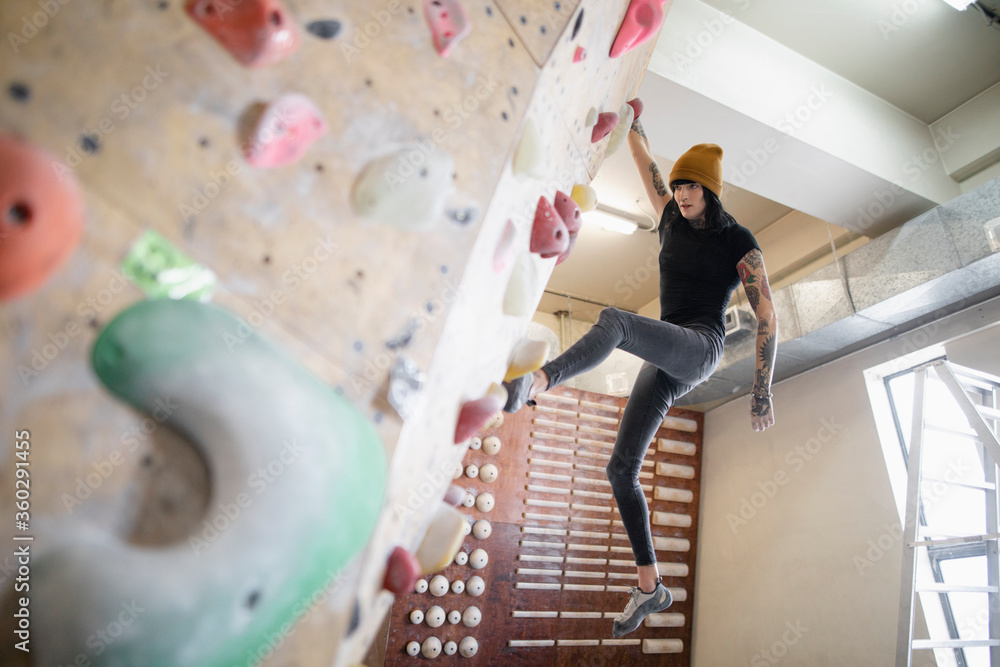 Young transgender woman hanging from indoor rock climbing wall Stock ...