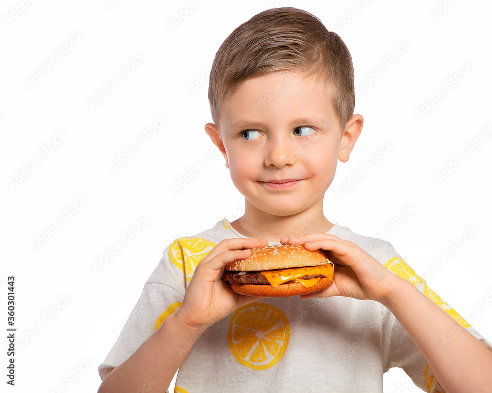 A child eats a cheeseburger. The boy holding the Burger looks around ...