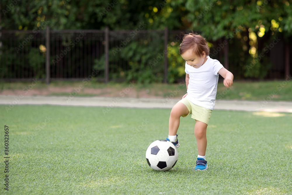 Toddler boy stopping soccer ball at football field. Little football ...