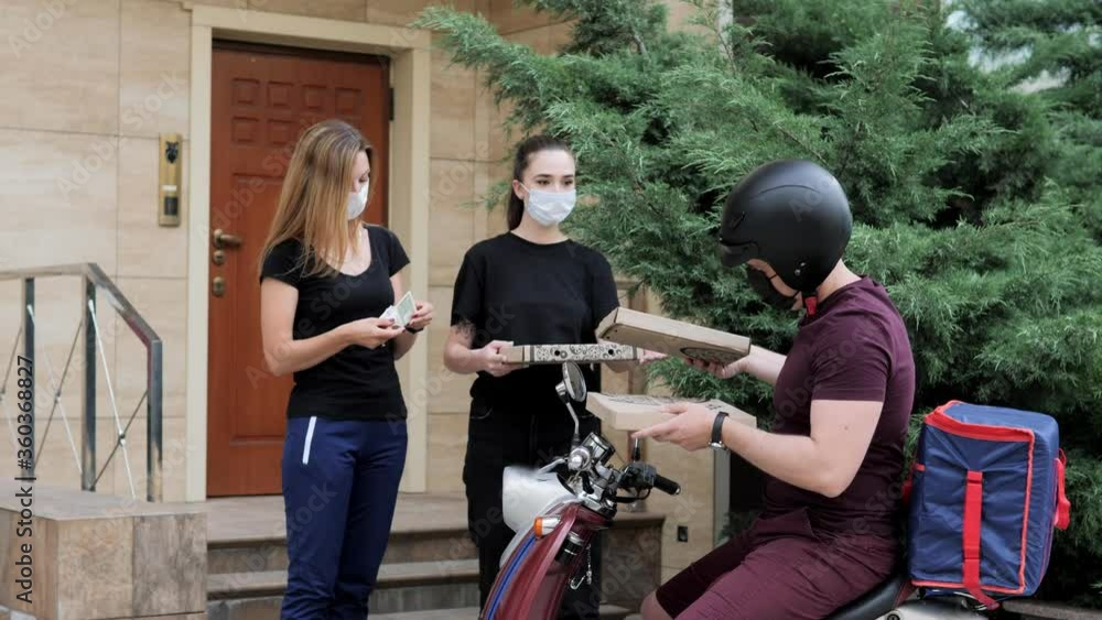 Two girls pick up delivery food box from delivery rider with scooter in ...