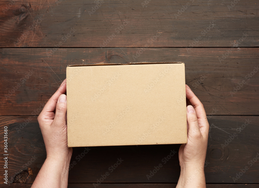 two hands holding a rectangular cardboard box of brown kraft paper ...