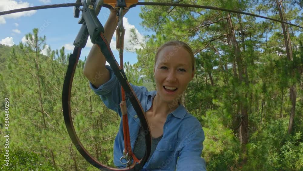 Vidéo Stock A young woman rides a zip line in an adventure park. She ...