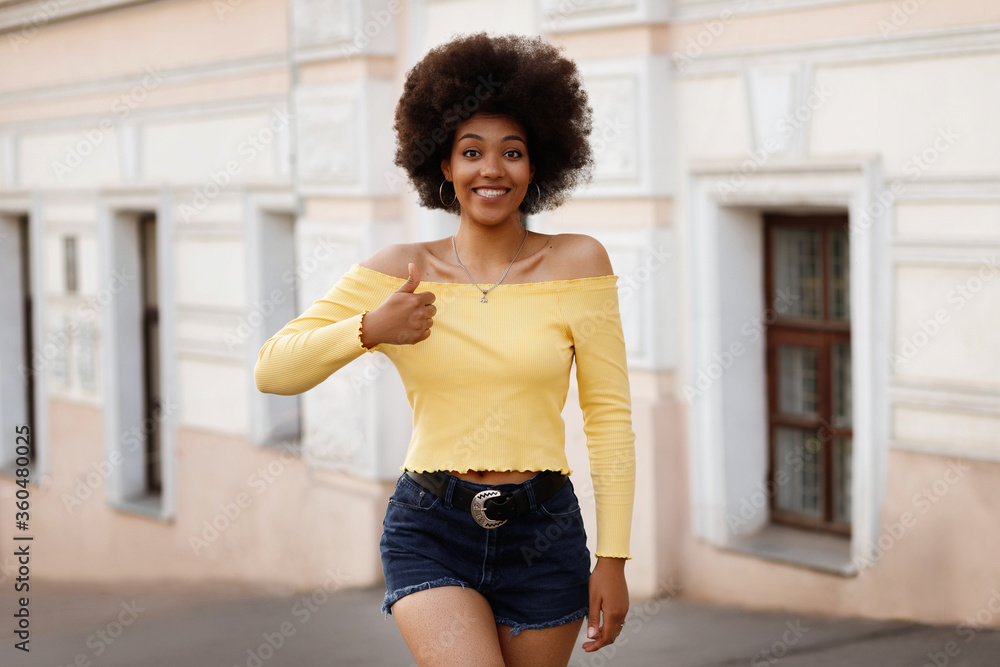 dark-skinned African American shows off a sign with her hand and smiles ...