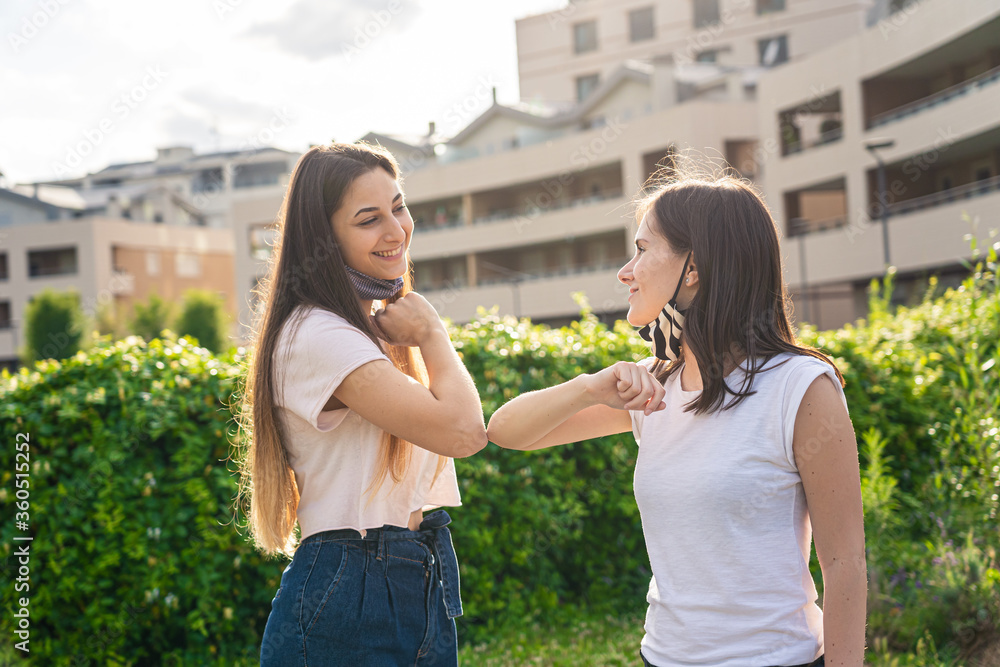 Friends saying hello with the elbow - two girls staying safe using a ...