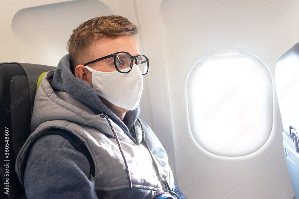Serious guy, young man on airplane, plane in glasses and medical ...