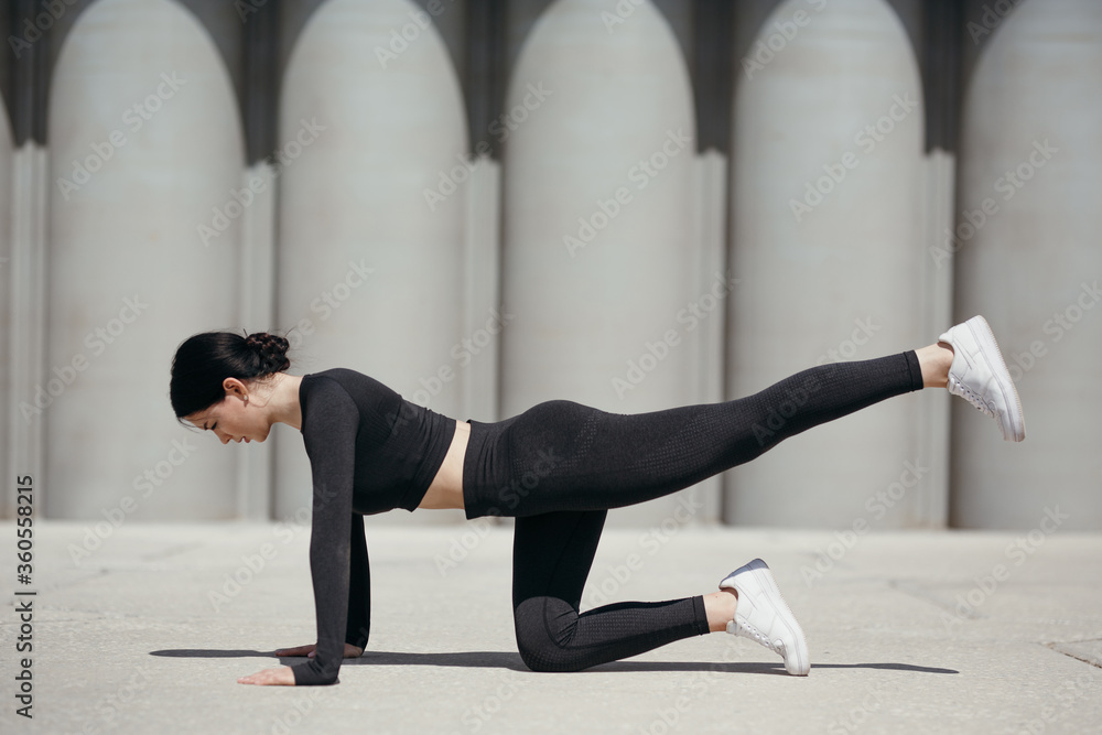 Fitness trainer in a tight-fitting tracksuit stands on all fours and ...
