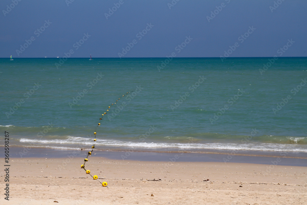 Tropical sandy beach with a rope on the beach and at the blue sea and ...