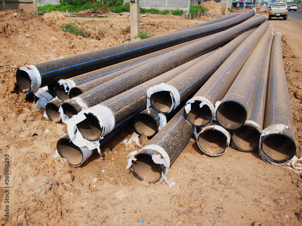Black HDPE plumbing on the ground beside the road. Round plastic pipes ...