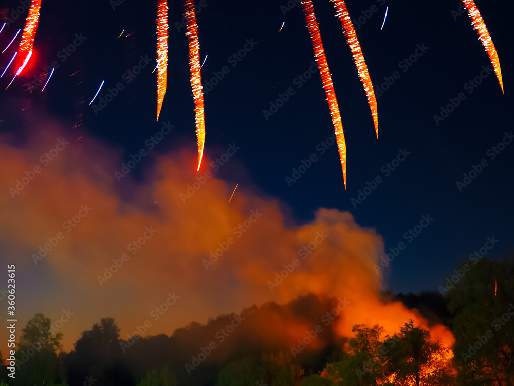 Fire at night in the park due to fireworks. Fire and smoke after ...