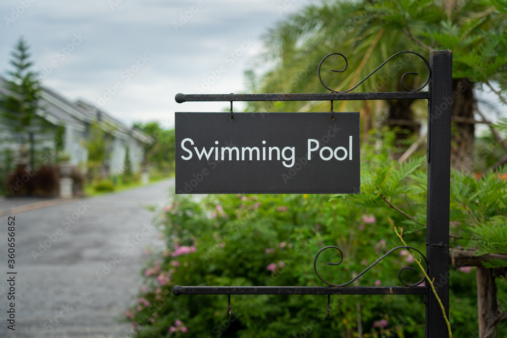 "Swimming pool" direction sign on black metal plate with background of ...