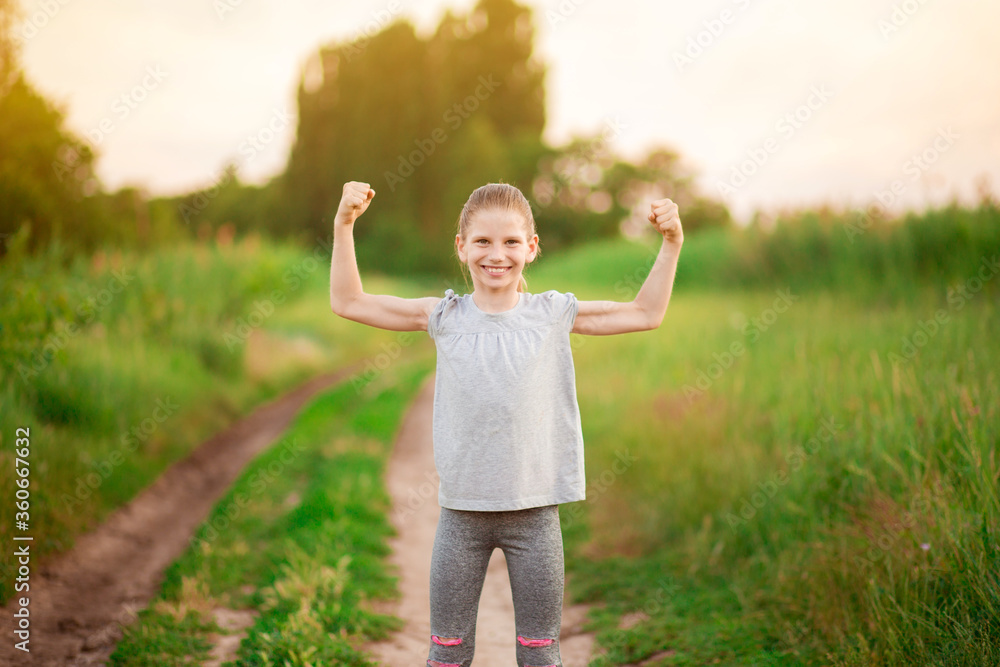 Child cute girl show biceps gesture of power and strength outdoor. Feel ...