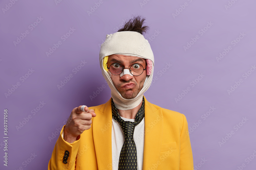 Angry man with bruises and bandaged head points directly at you, blames ...