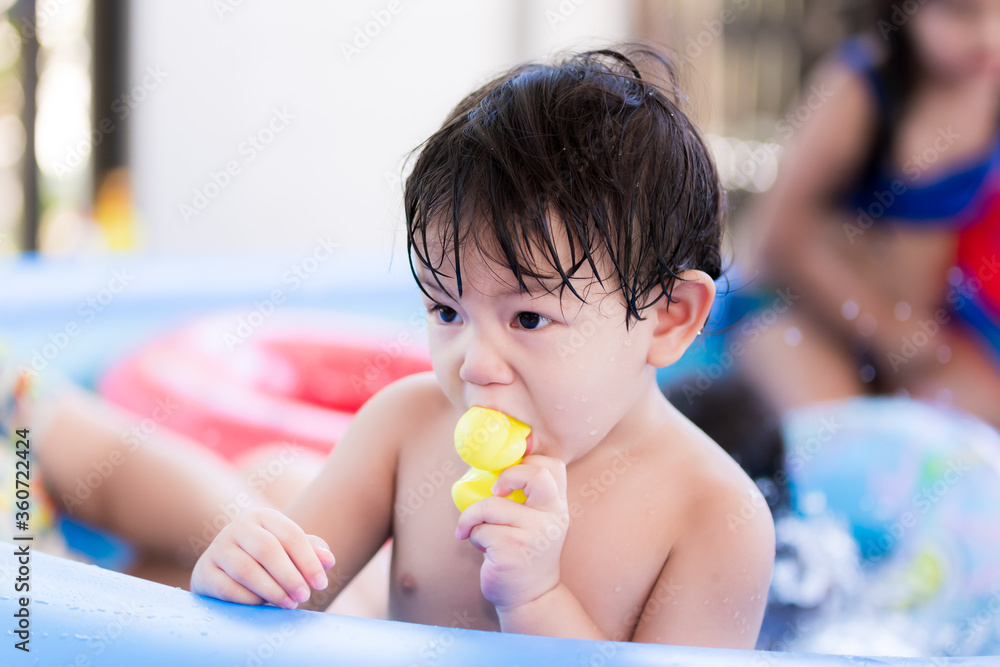 Adorable baby boy plays in the blue rubber pool. The little boy is ...