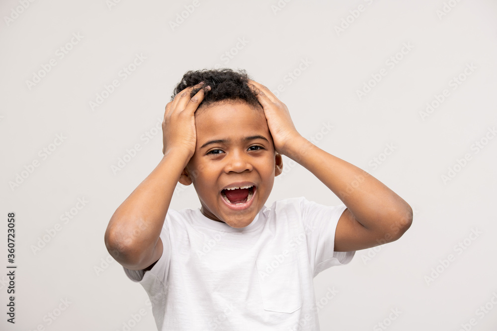 Extremely happy cute little boy touching head by hands and shouting in ...