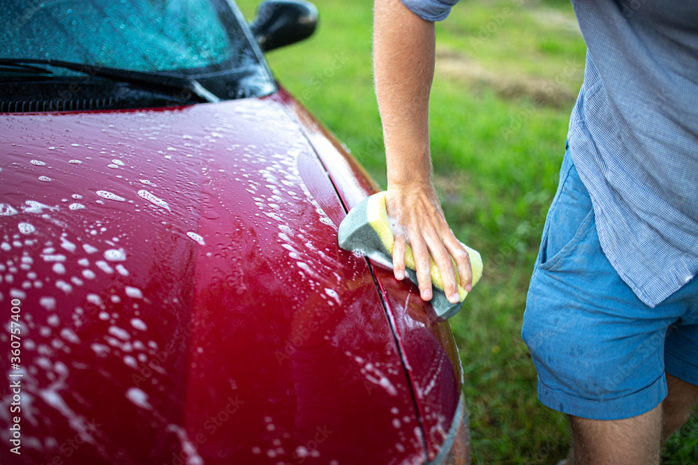 washing a red car with hands, a hook with foam on the back of a car ...