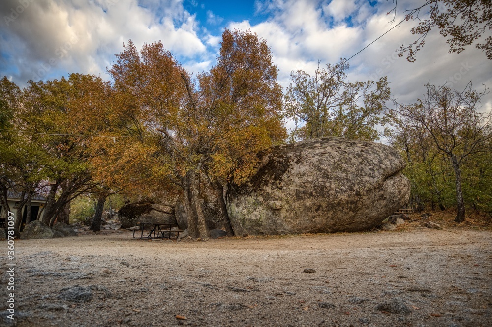 Huge rock on the side of a road with trees under the cloudy sky Stock ...