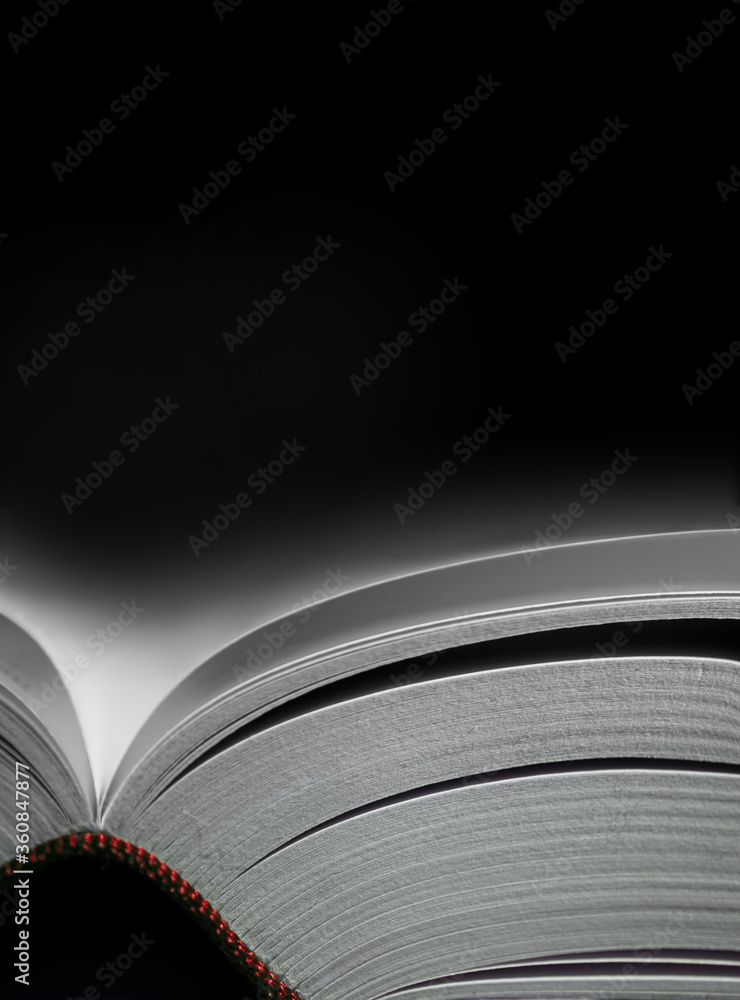 Vertical image of an open book with red cover and dark background with ...