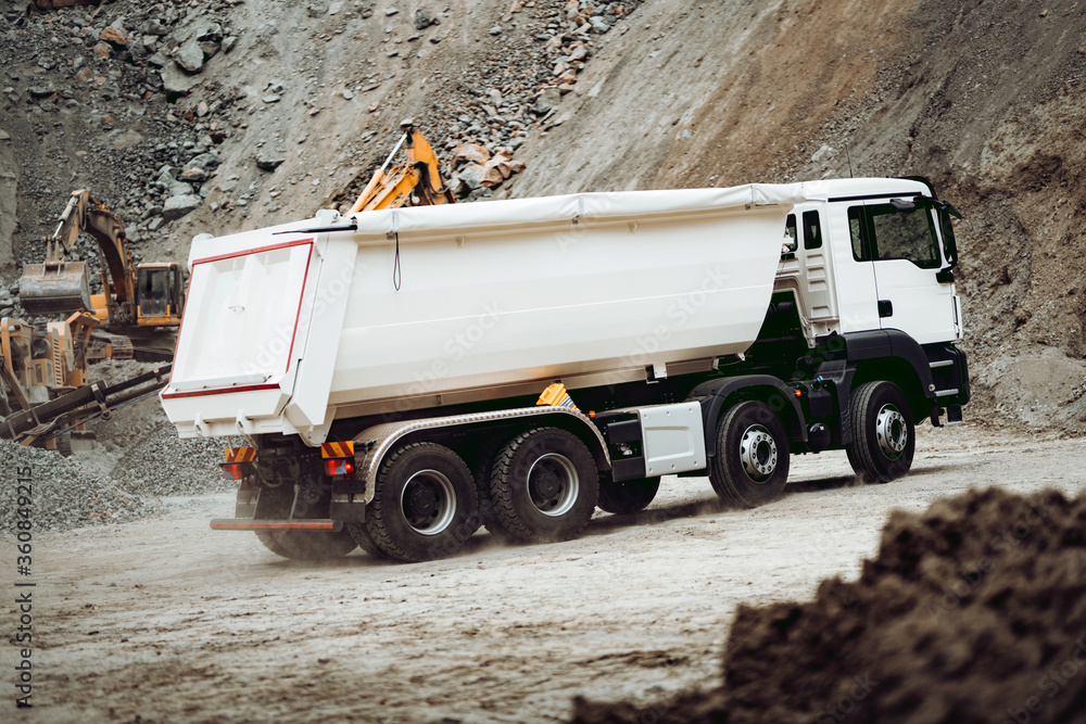 Industrial dumper trucks working on construction site, loading and ...