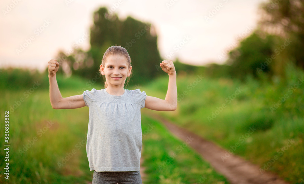 Child cute girl show biceps gesture of power and strength outdoor. Feel ...