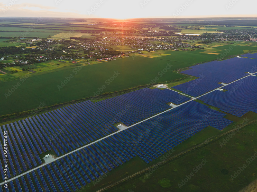 Aerial drone view into large solar panels at a solar farm at bright ...