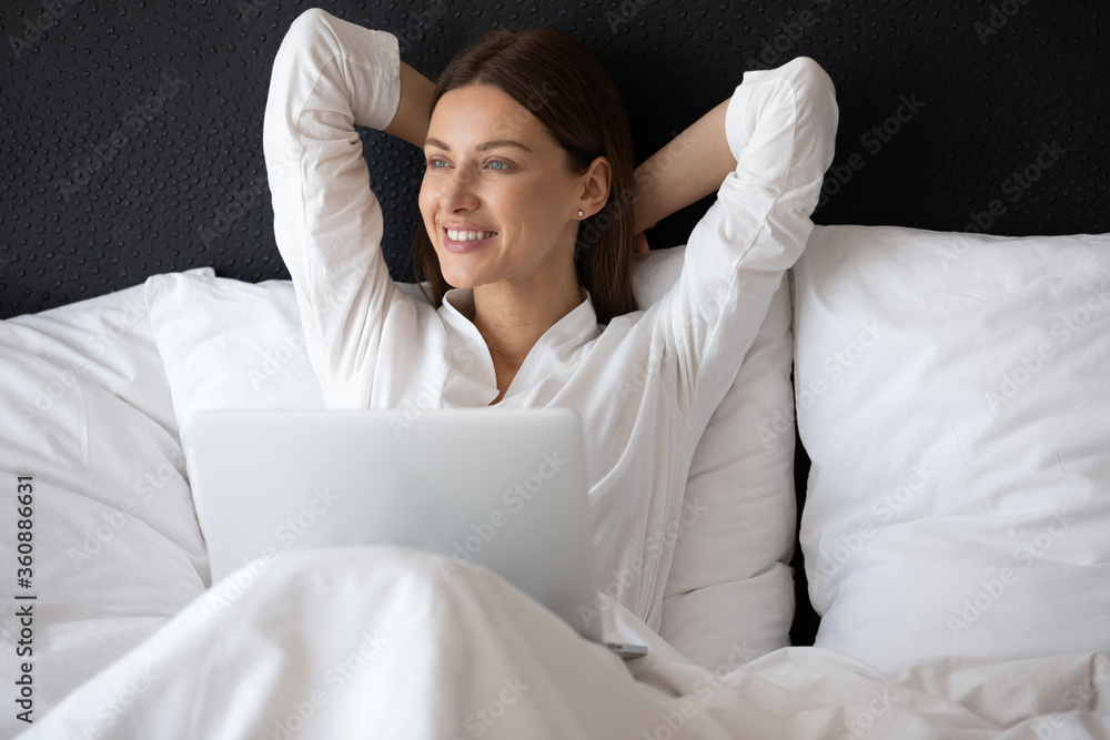 Smiling young woman in white bathrobe rest in comfortable bed at home ...