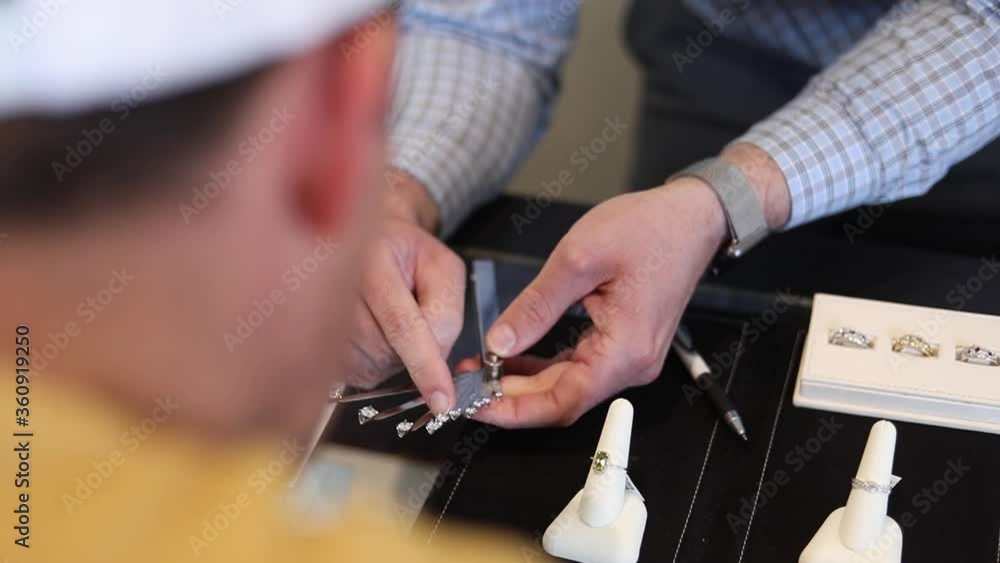 Jeweler points to different diamond sizes of diamonds. Jewelry Salesman ...
