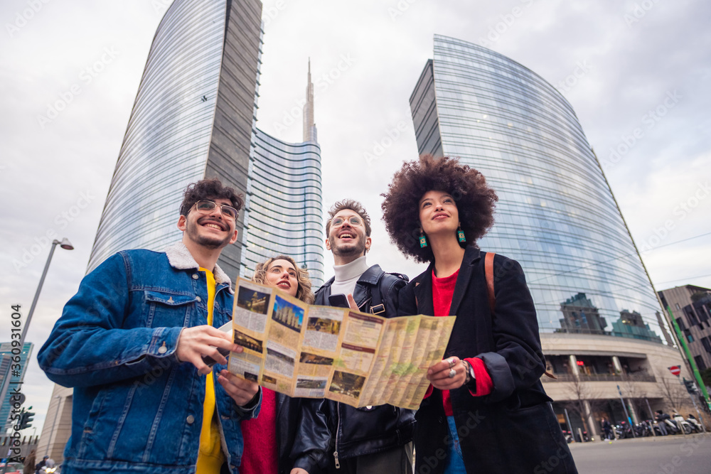 Four multiethnic people tourist using map - Friends traveller outdoors ...