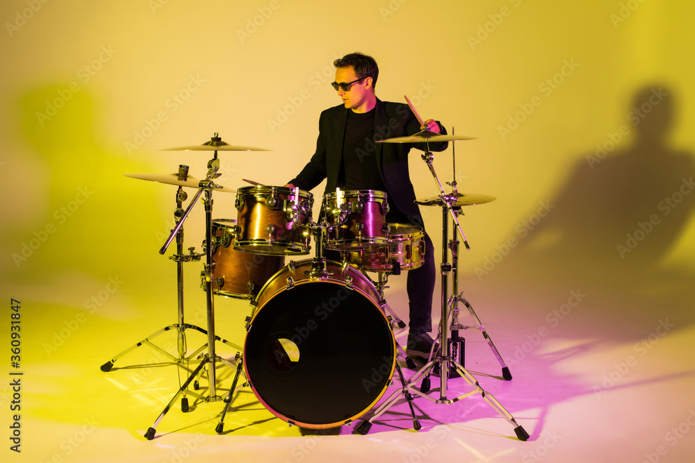 Caucasian male drummer improvising isolated on light studio background ...