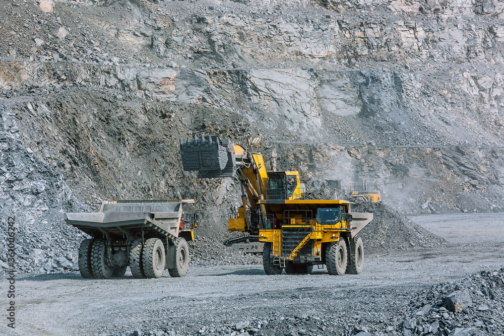Excavator loads ore into a mining dump truck. Stock Photo | Adobe Stock