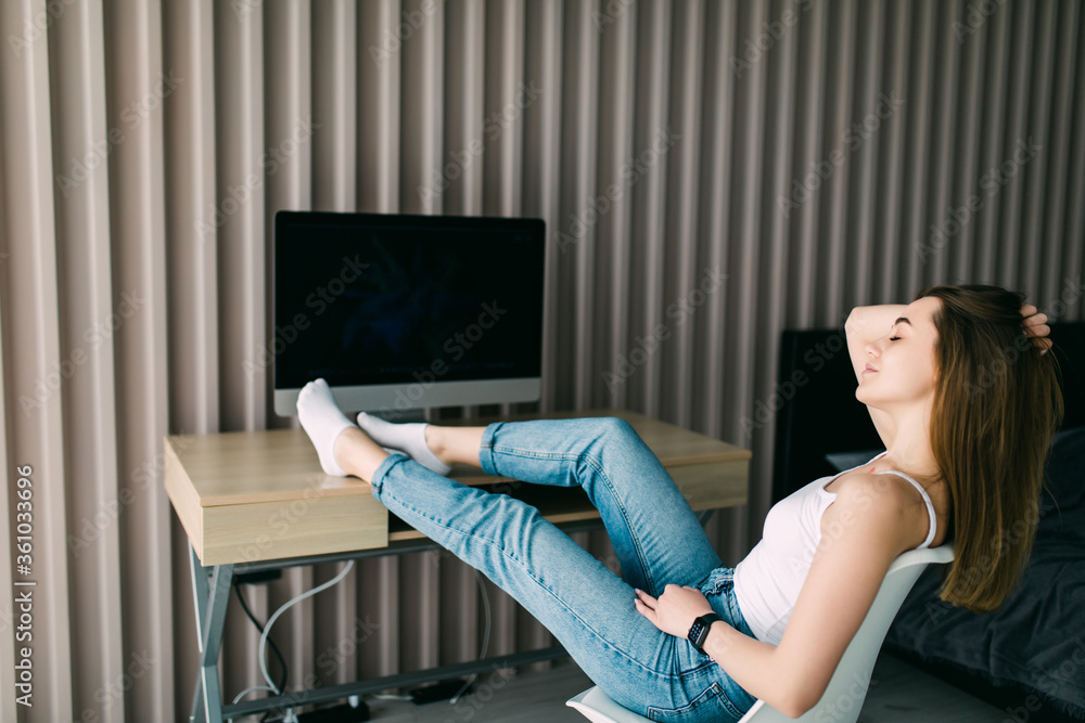 Young woman taking time out to relax at home sitting with her bare feet ...