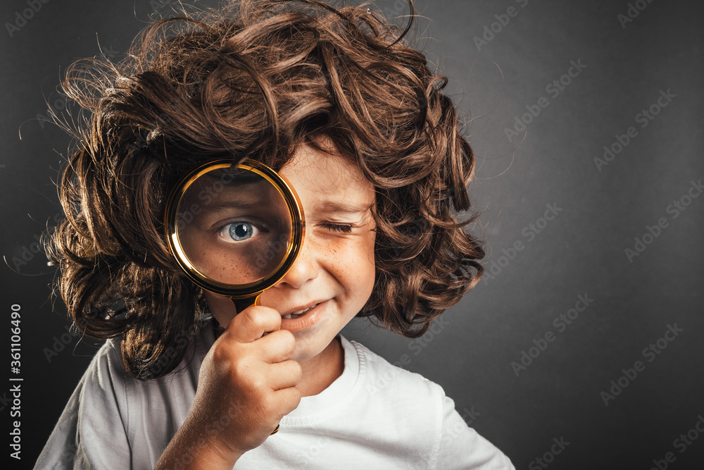 Child see through magnifying glass on the black backgrounds. Big kid ...