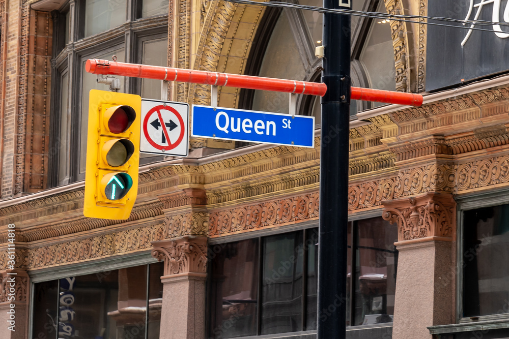 Closeup sign of Queen St and traffic light with historic building in ...