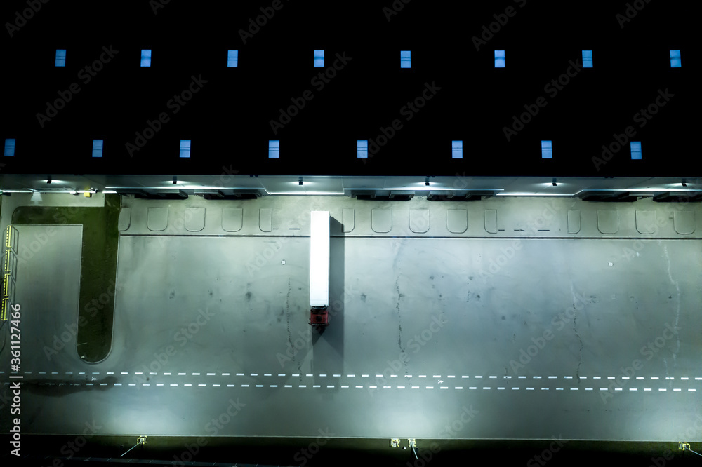 Night Aerial view of trucks unloading in logostics center. Logistics ...