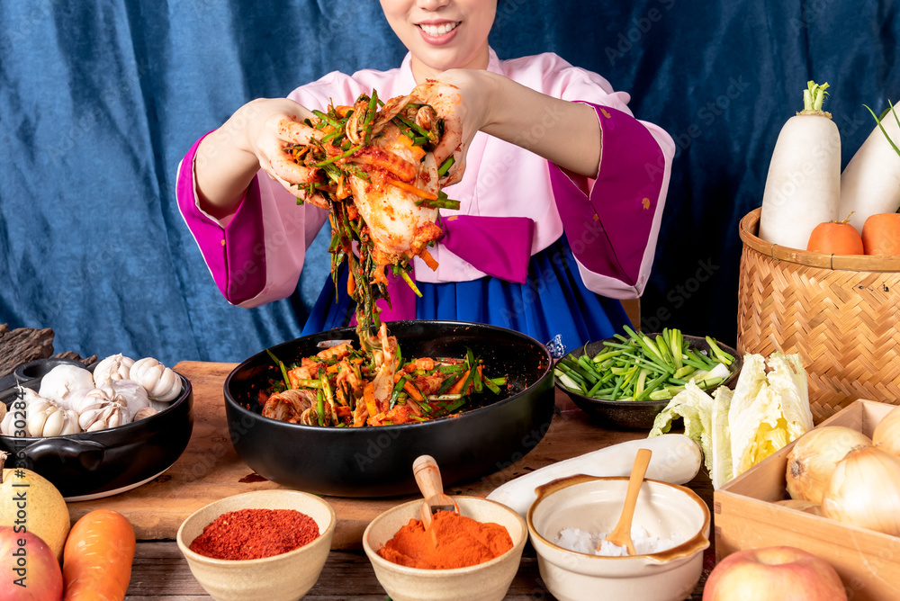 Korean woman is wearing a traditional hanbok, she making Kimchi which ...